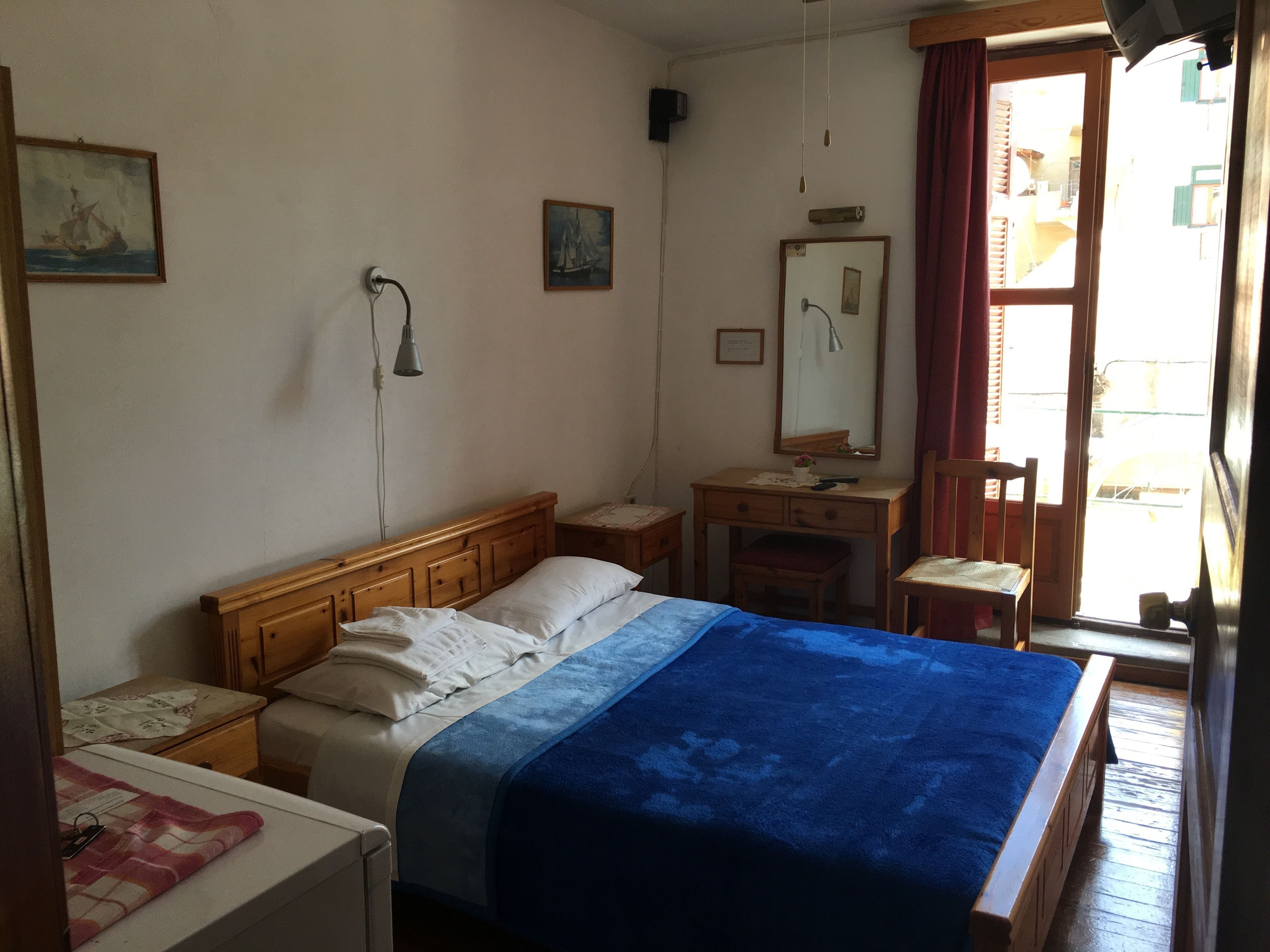 Quarto com cama, escrivaninha, cadeira, cômoda e espelho.