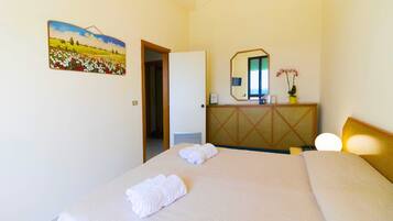 Quarto de hotel com cama, toalhas, um quadro, espelho e abajur.
