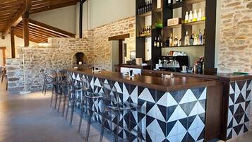Uma área de bar com parede de pedra, teto de madeira e balcão revestido com design geométrico em azulejos.