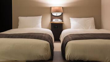 Quarto de hotel com duas camas, uma mesa de cabeceira com abajur e um relógio digital.