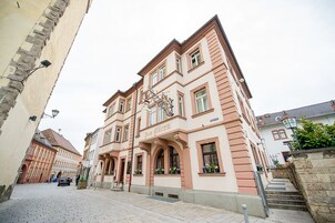 Um edifício histórico com estilo arquitetônico clássico, apresentando janelas em arco e uma entrada central.
