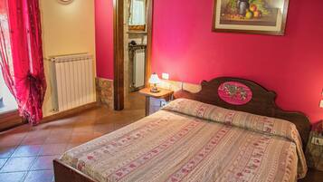 Quarto com cama, mesa de cabeceira, espelho e janela com cortinas.