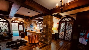 Um interior rústico com piso de madeira, paredes de pedra, um espaço de bar e um tapete de couro de vaca.