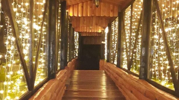 Uma ponte de madeira decorada com luzes e corrimãos, e com piso em madeira.