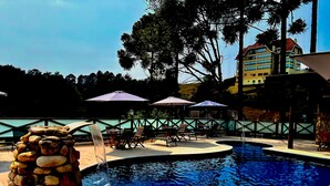 Piscina com estrutura de pedra, espreguiçadeiras e guarda-sóis.