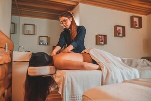 Sala de massagem com teto de madeira, mesa de massagem e uma pia pequena.