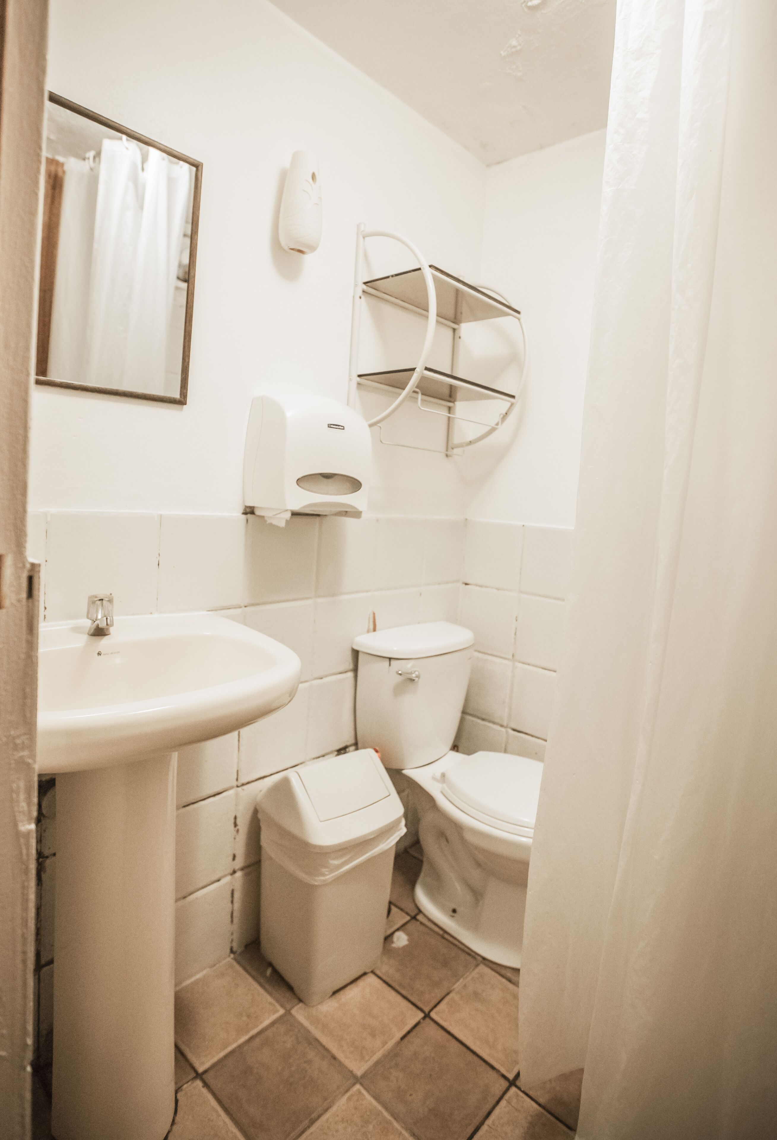 Casa de banho com lavatório, sanita e um cesto de lixo.