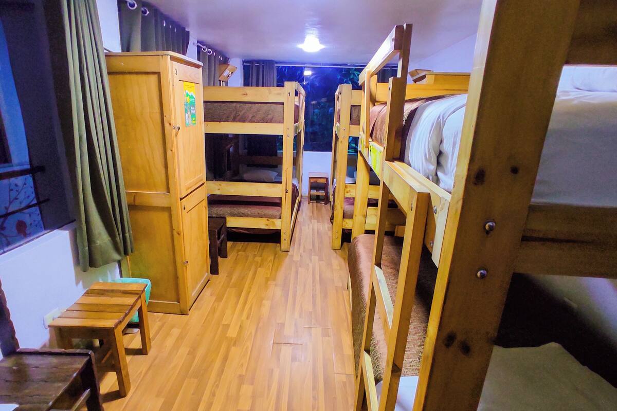 Um corredor estreito com beliches em ambos os lados, armários de madeira e uma pequena mesa.