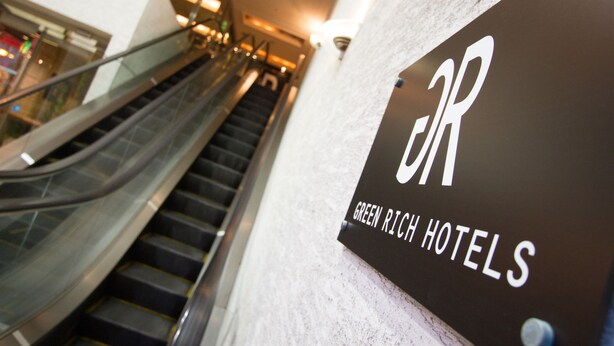 Escada rolante que leva a um letreiro para Green Rich Hotels.
