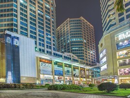 Um edifício moderno com vários andares, janelas amplas e sinalização iluminada.