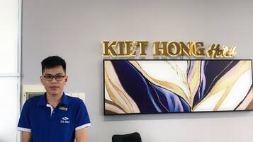 Uma receção de hotel com uma placa a dizer "TIẾP TÂN RECEPTION" e uma grande placa na parede com a inscrição "KIẾT HONG Hotel".