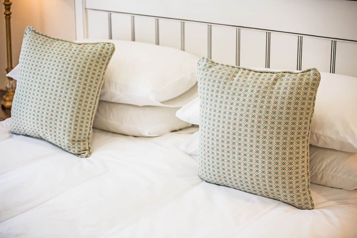 Cama com roupa de cama branca e almofadas estampadas.