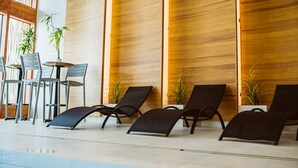 Uma área interna de piscina moderna com cadeiras de descanso e uma mesa.