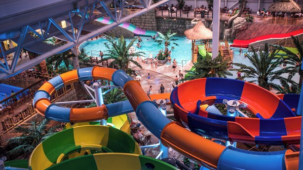 Um parque aquático interno com vários toboáguas e uma área de piscina central.