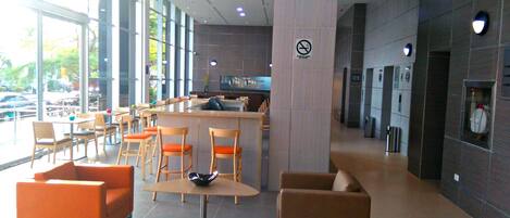 Espaço moderno em ambientes internos com área de bar, assentos e vista para o exterior.