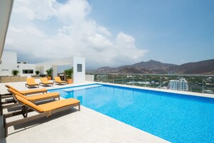 Piscina no terraço com espreguiçadeiras e vista para as montanhas.
