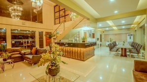 Um hall amplo com balcão de recepção, área de estar, escada e espaço de refeições.