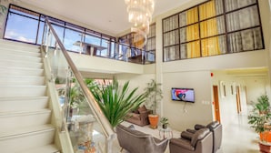 Um hall espaçoso com escada, área de estar e uma grande janela com cortinas.