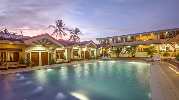 Um hotel com piscina, vários quartos de hóspedes e área externa coberta.