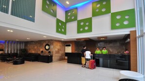Um saguão de hotel com balcão de recepção, área de estar e uma grande janela.