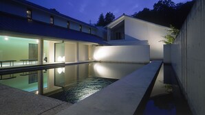 Um edifício moderno com piscina, varanda coberta e céu claro ao anoitecer.