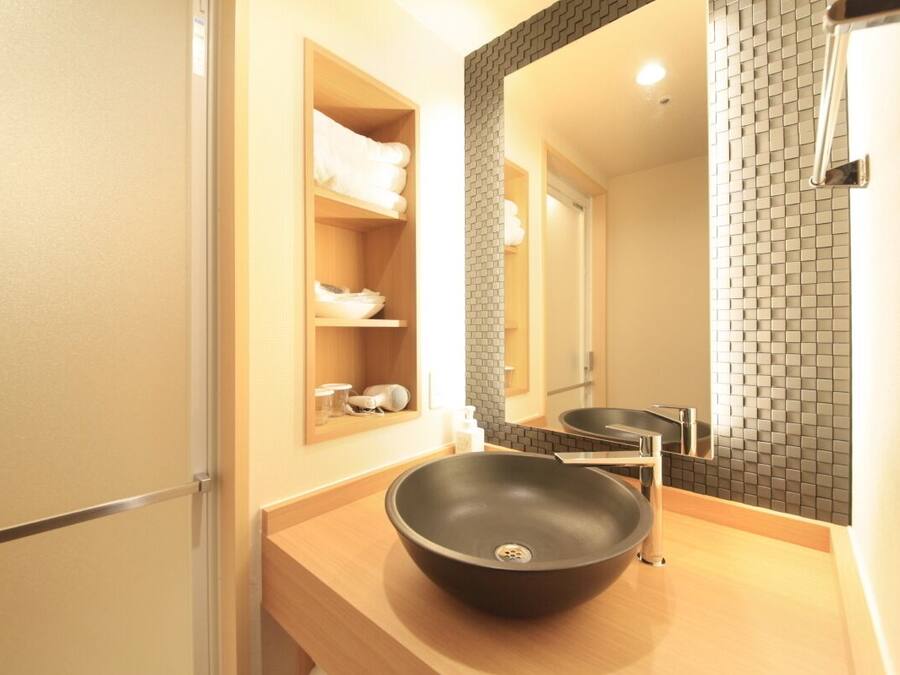 Casa de banho moderna com lavatório preto, espelho e prateleira com toalhas.