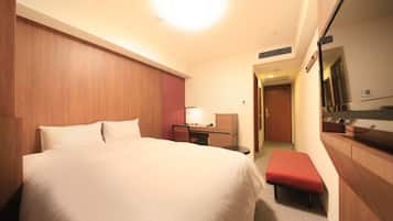 Quarto de hotel com uma cama grande, uma mesa com cadeira, um pequeno banco, um espelho e uma porta que dá para outro cômodo.