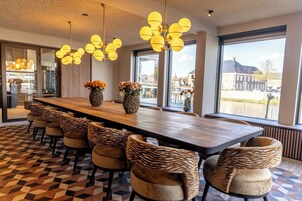 Uma área de refeições moderna com uma mesa comprida, cadeiras com padrão de zebra e janelas amplas com vista.