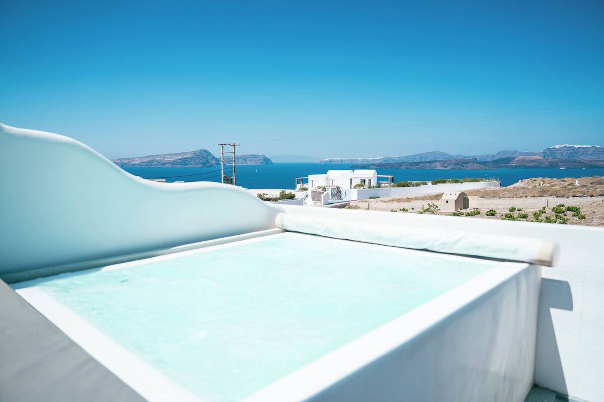 Quarto de hotel moderno com ampla vista para o mar e montanhas ao longe.