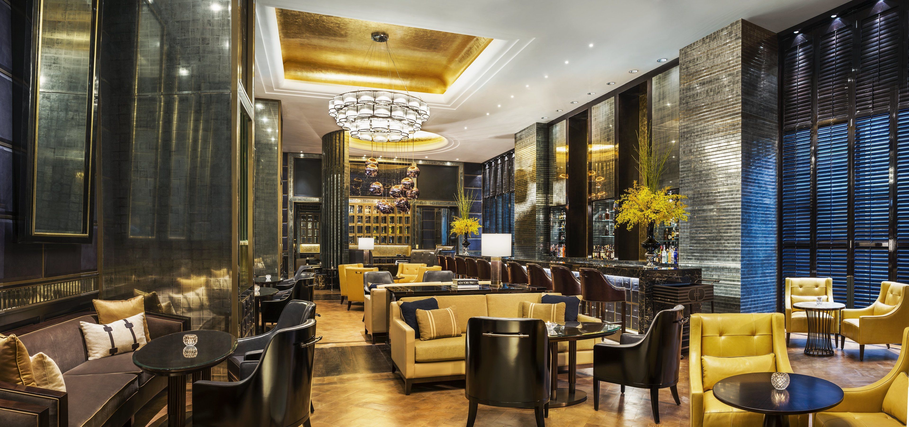 Um lobby luxuoso com área de bar, espaços de estar e um candelabro.