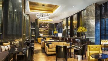 Um lobby luxuoso com área de bar, espaços de estar e um candelabro.