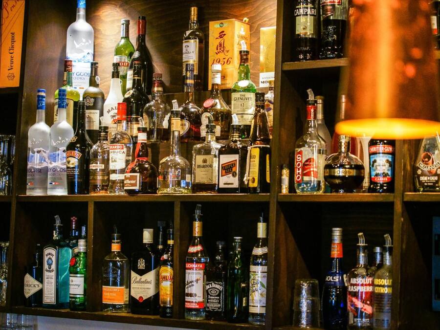 Um bar com prateleiras repletas de garrafas de bebidas alcoólicas.