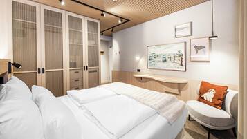 Quarto de hotel moderno com uma cama grande, espaço de estar e teto de madeira.