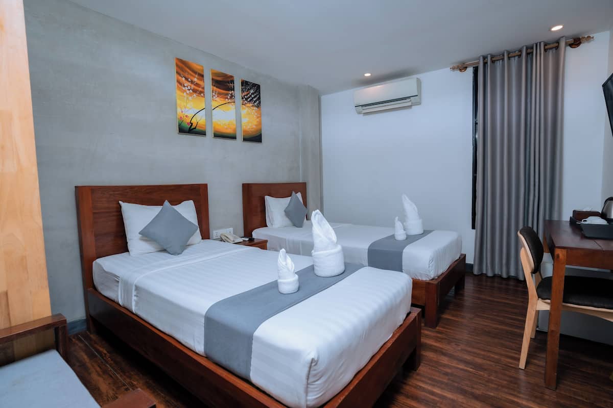 Quarto de hotel com duas camas, uma escrivaninha e uma cadeira.