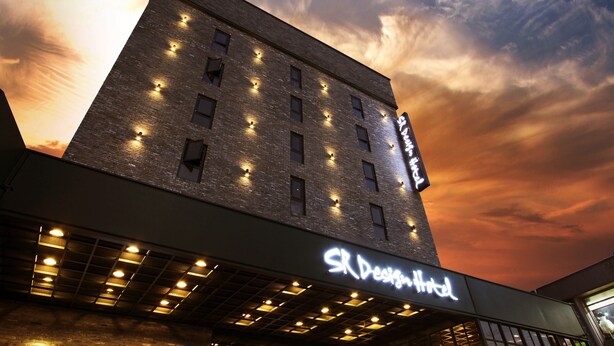 Hotel com fachada moderna de tijolos e janelas iluminadas.