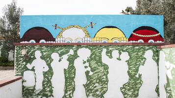 Um mural com figuras humanas estilizadas e céu azul.