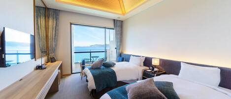 Quarto de hotel com duas camas, uma escrivaninha e varanda com vista.