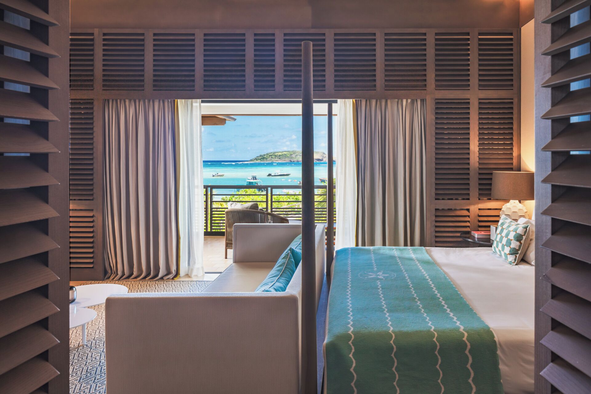 Quarto de hotel com varanda, cama, sofá e mesa.