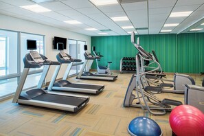 Uma academia com esteiras, elípticos e bolas de exercício.