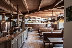 Restaurante com vigas de madeira, chão em azulejo e várias áreas de refeição, incluindo cabines e mesas.