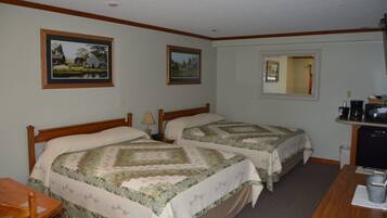 Quarto de hotel com duas camas de solteiro, uma escrivaninha, uma cadeira, cafeteira e uma pequena lixeira.