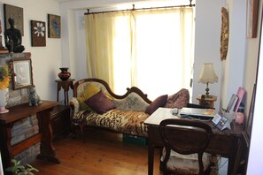Um quarto aconchegante com uma cama de madeira, uma escrivaninha com um computador e diversos objetos decorativos nas paredes.