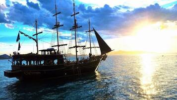 Um grande navio a vela com vários mastros e estrutura de cabine, navegando em águas calmas.