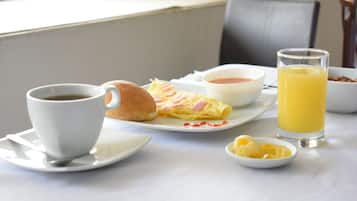Uma mesa posta para o café da manhã, com xícara de café, croissant, tigela de sopa, copo de suco de laranja e uma pequena tigela de manteiga.
