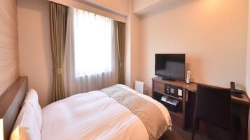 Quarto de hotel com uma cama grande, uma escrivaninha com televisão e uma cadeira.