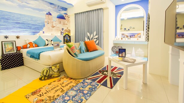 Uma sala de estar com um sofá, um gato, uma mesa e um mural na parede.