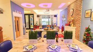 Uma sala de jantar com uma mesa comprida posta para quatro pessoas, parede de tijolos e uma árvore de Natal.