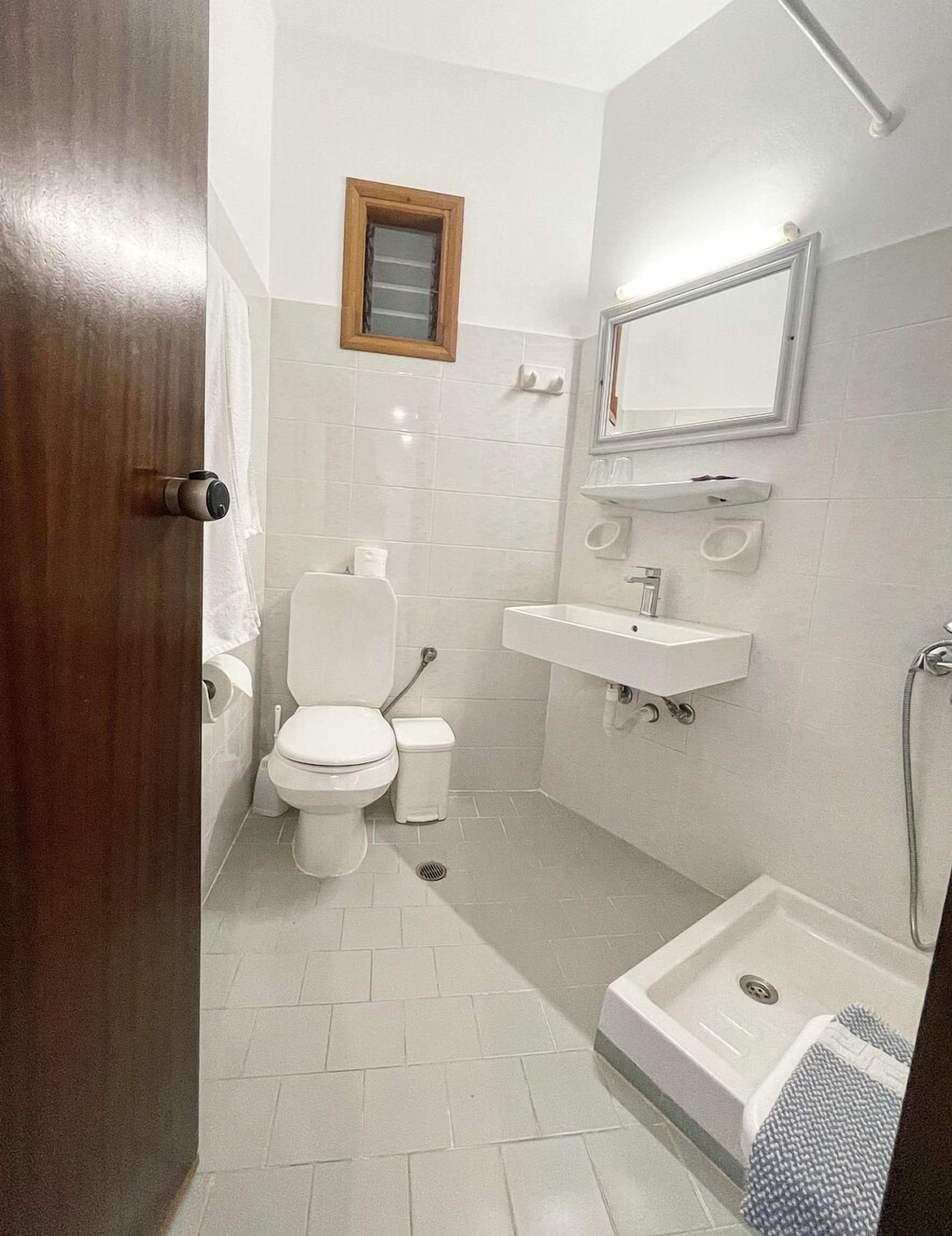 Uma casa de banho moderna com sanita, lavatório e chuveiro.