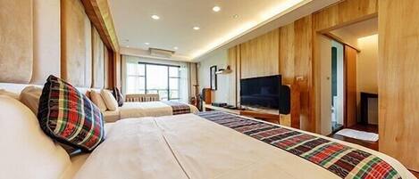 Quarto de hotel com uma cama grande, televisão e painéis de madeira.