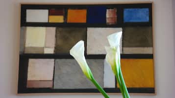 Uma pintura com formas geométricas abstratas e um vaso com flores brancas.
